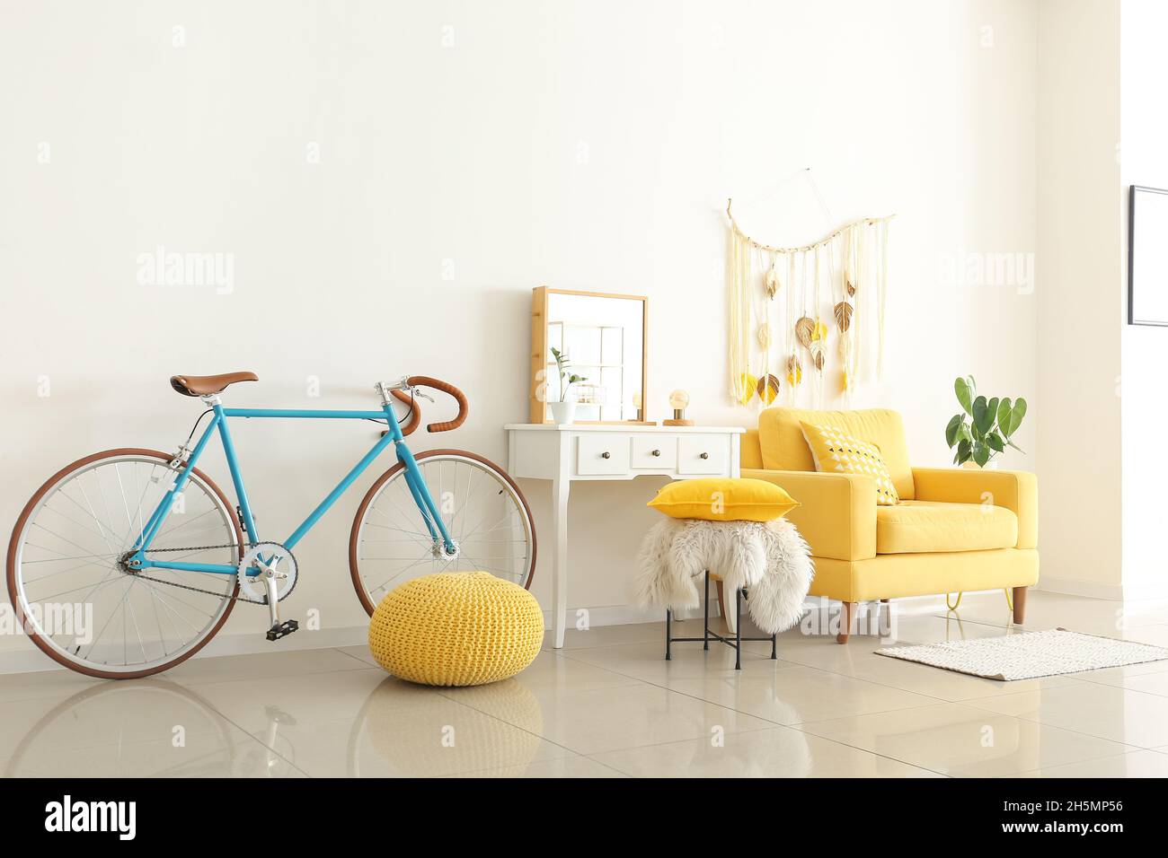 Interior of light room with yellow armchair, dressing table and bicycle ...