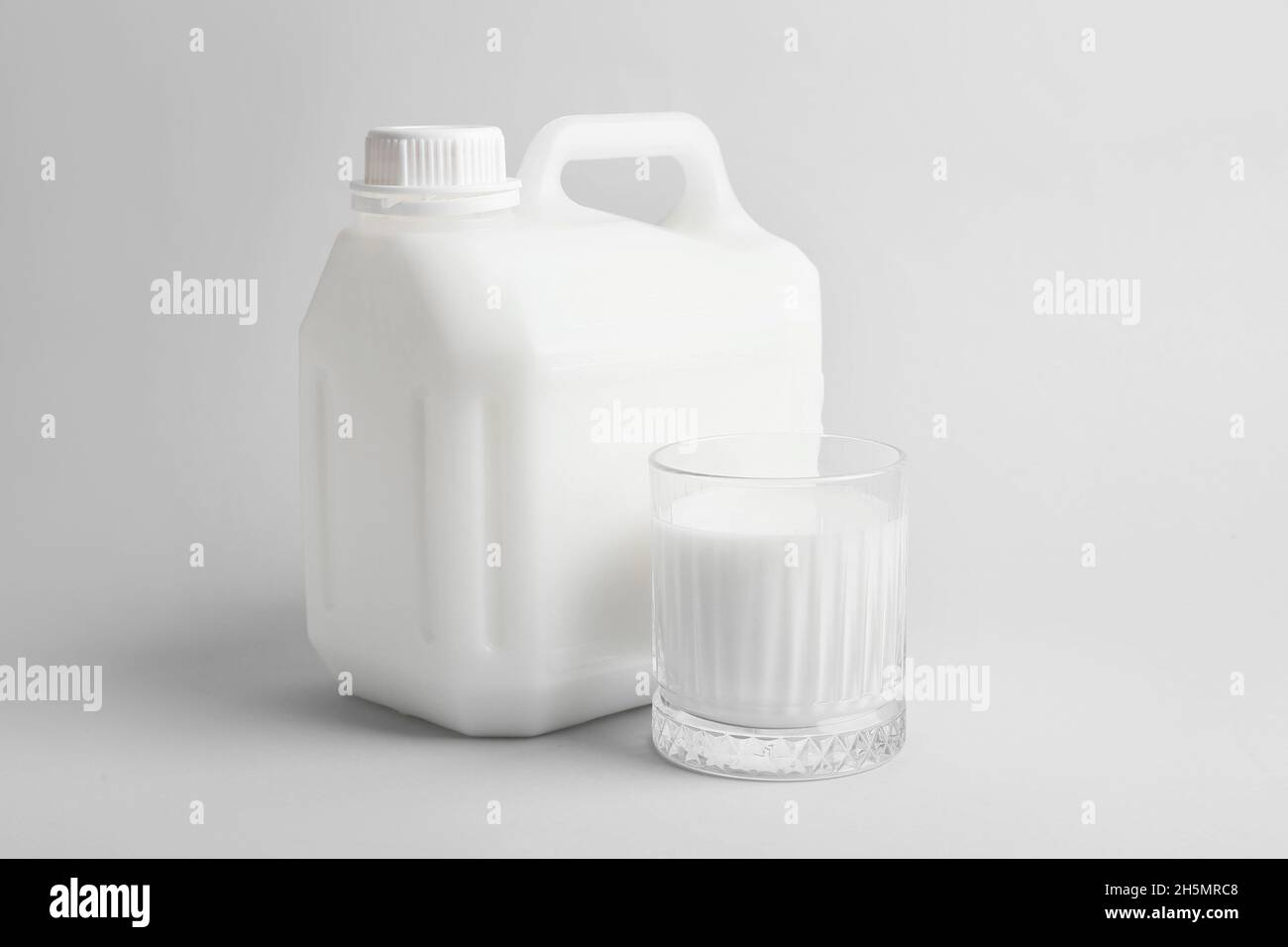 Gallon bottle and glass of milk on light background Stock Photo - Alamy