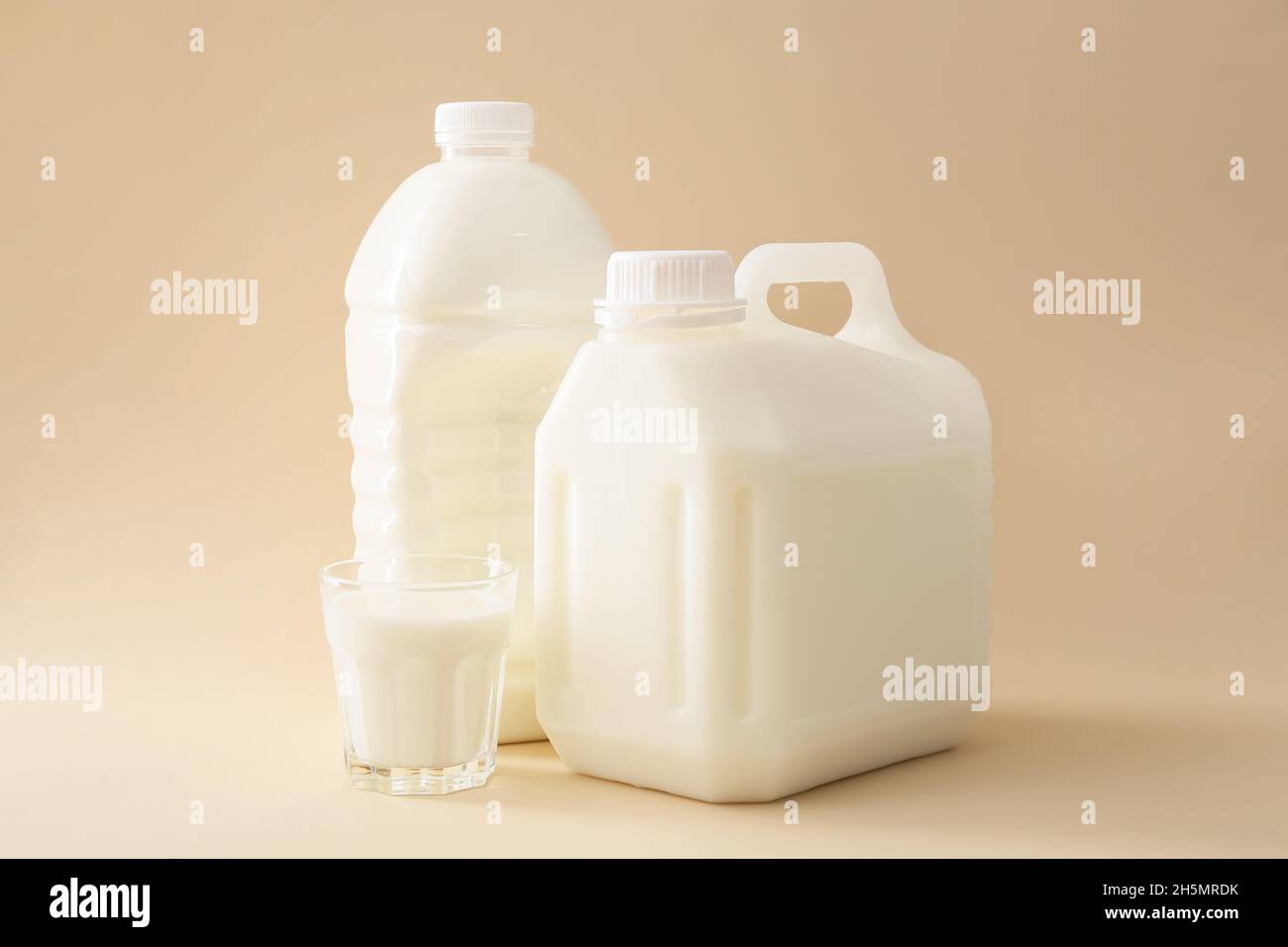 Gallon bottles and glass of milk on color background Stock Photo - Alamy