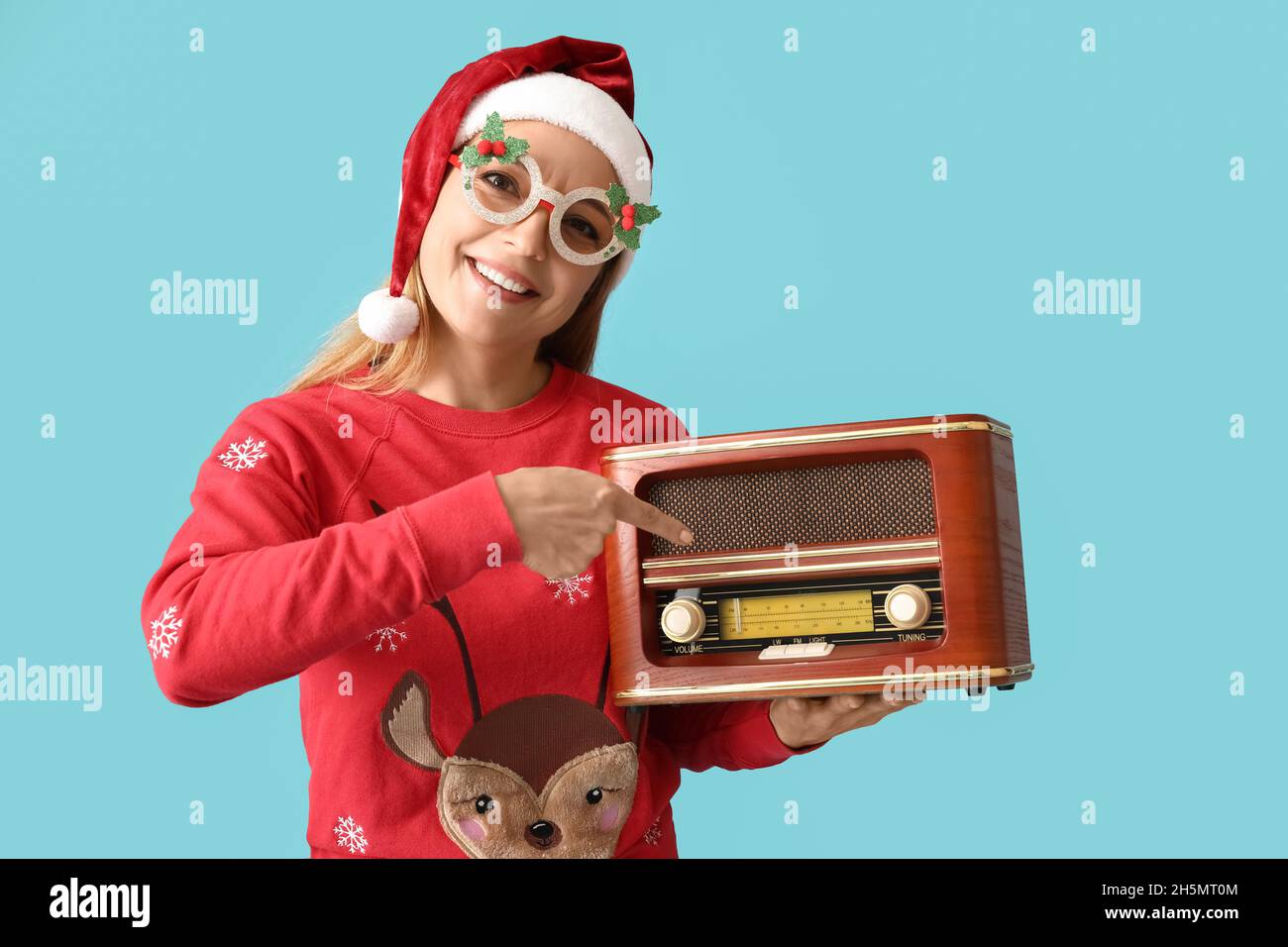 Mature woman with radio receiver listening to Christmas music on color ...