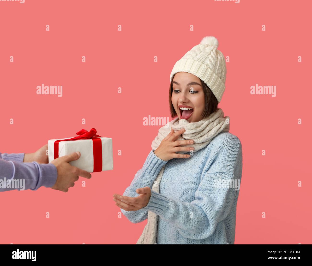 Young woman receiving Christmas gift from her boyfriend on color ...