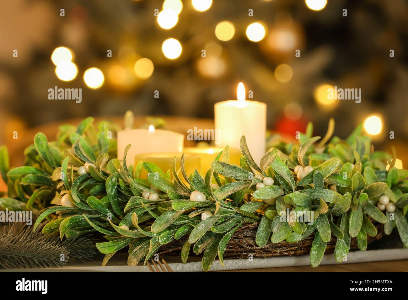 Beautiful mistletoe wreath with candles on table served for Christmas dinner Stock Photo - Alamy