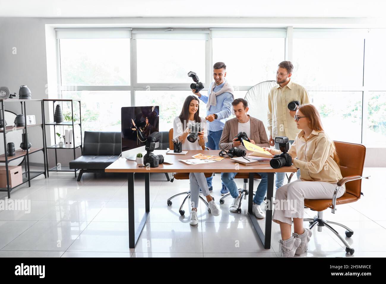 Professional photographer teaching young people in studio Stock Photo ...