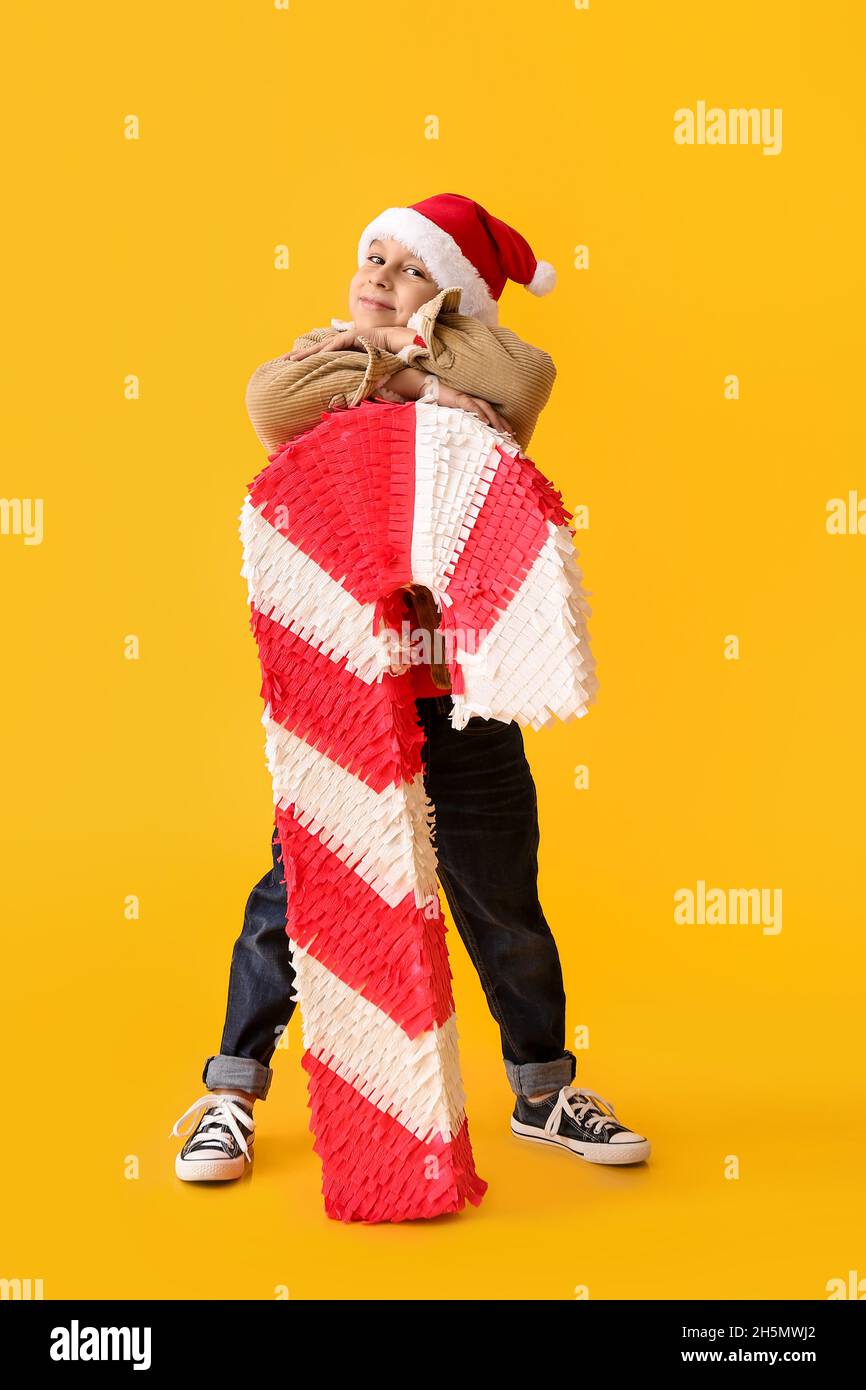 Cute little boy with candy cane pinata on color background Stock Photo ...