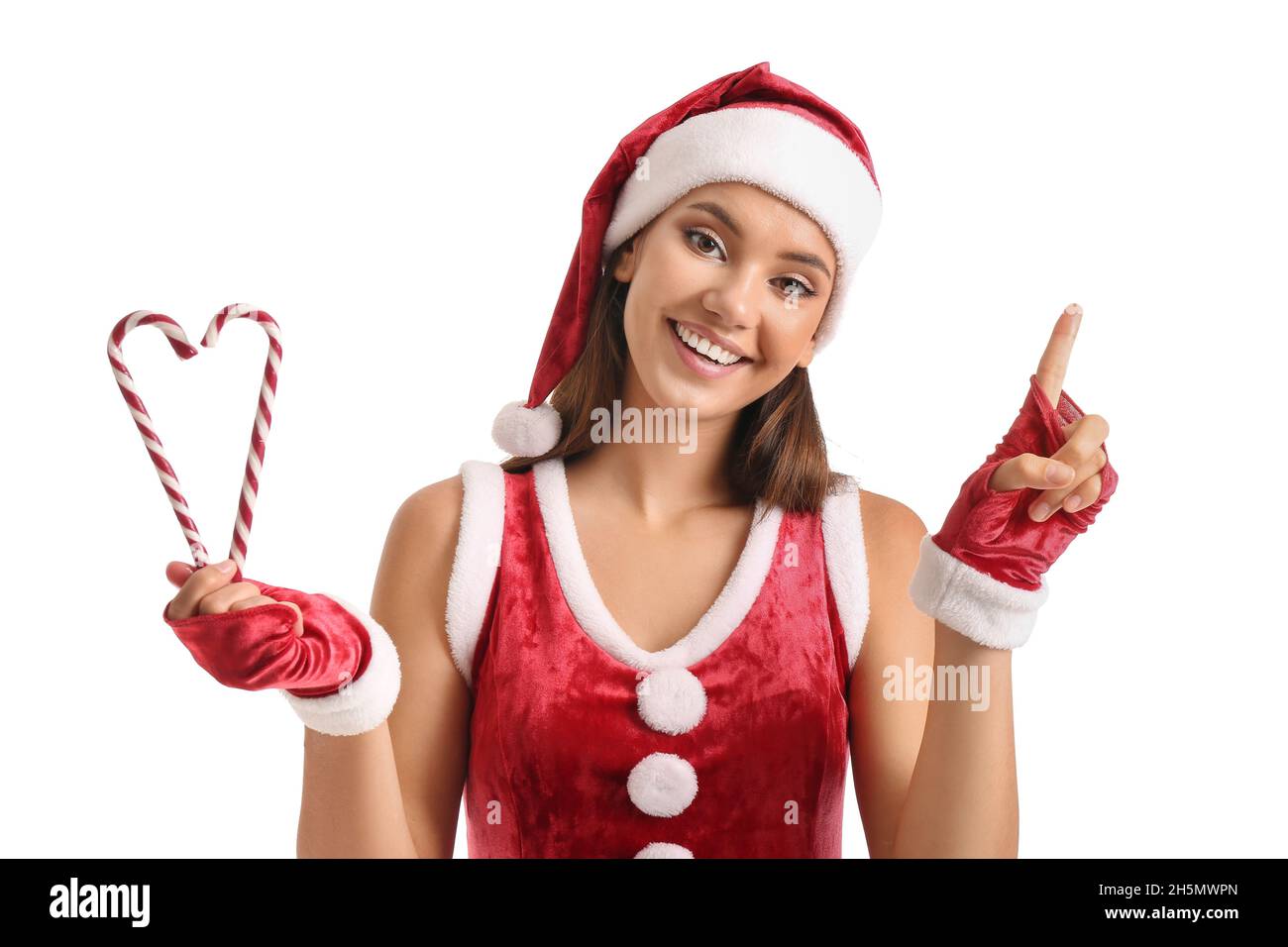 Beautiful woman in Santa costume and with candy canes pointing at ...