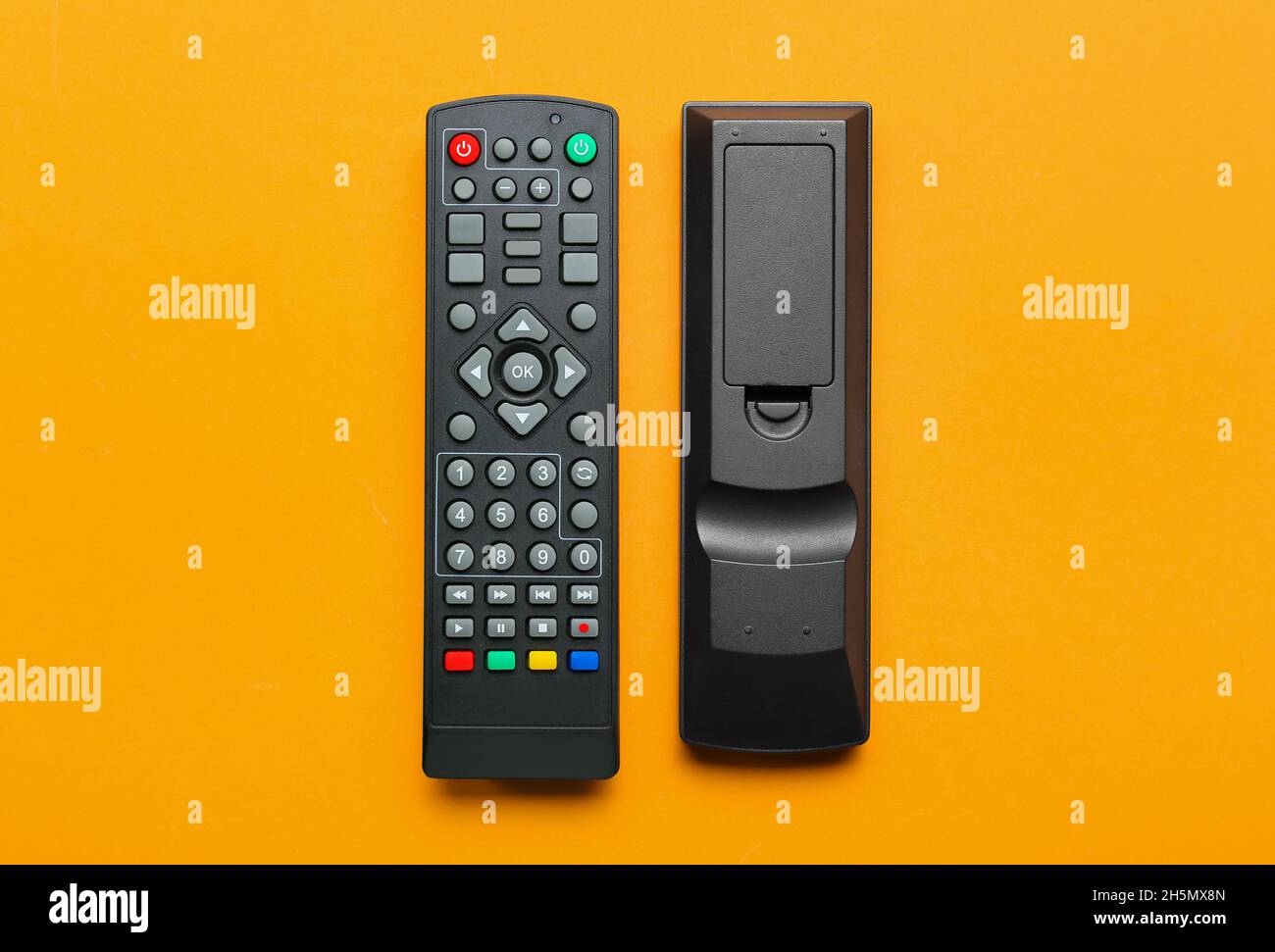 Modern TV remote controllers on orange background Stock Photo - Alamy