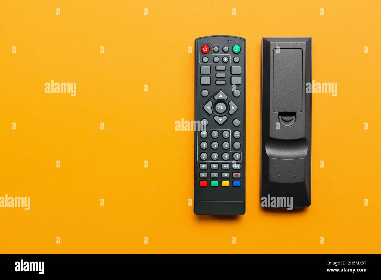 Modern TV remote controllers on orange background Stock Photo - Alamy