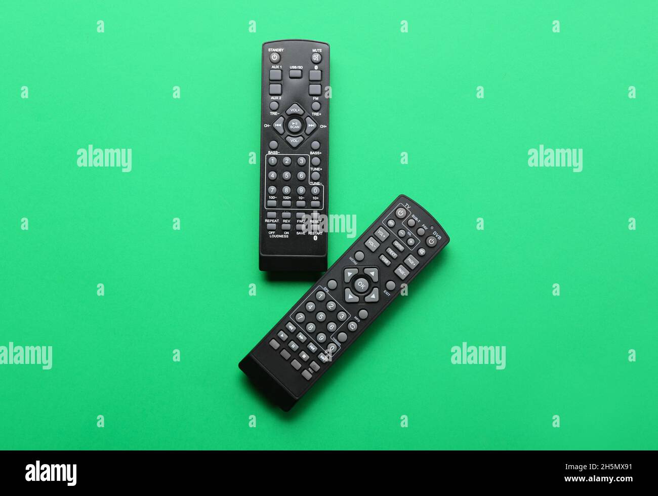 Modern TV remote controllers on green background Stock Photo - Alamy