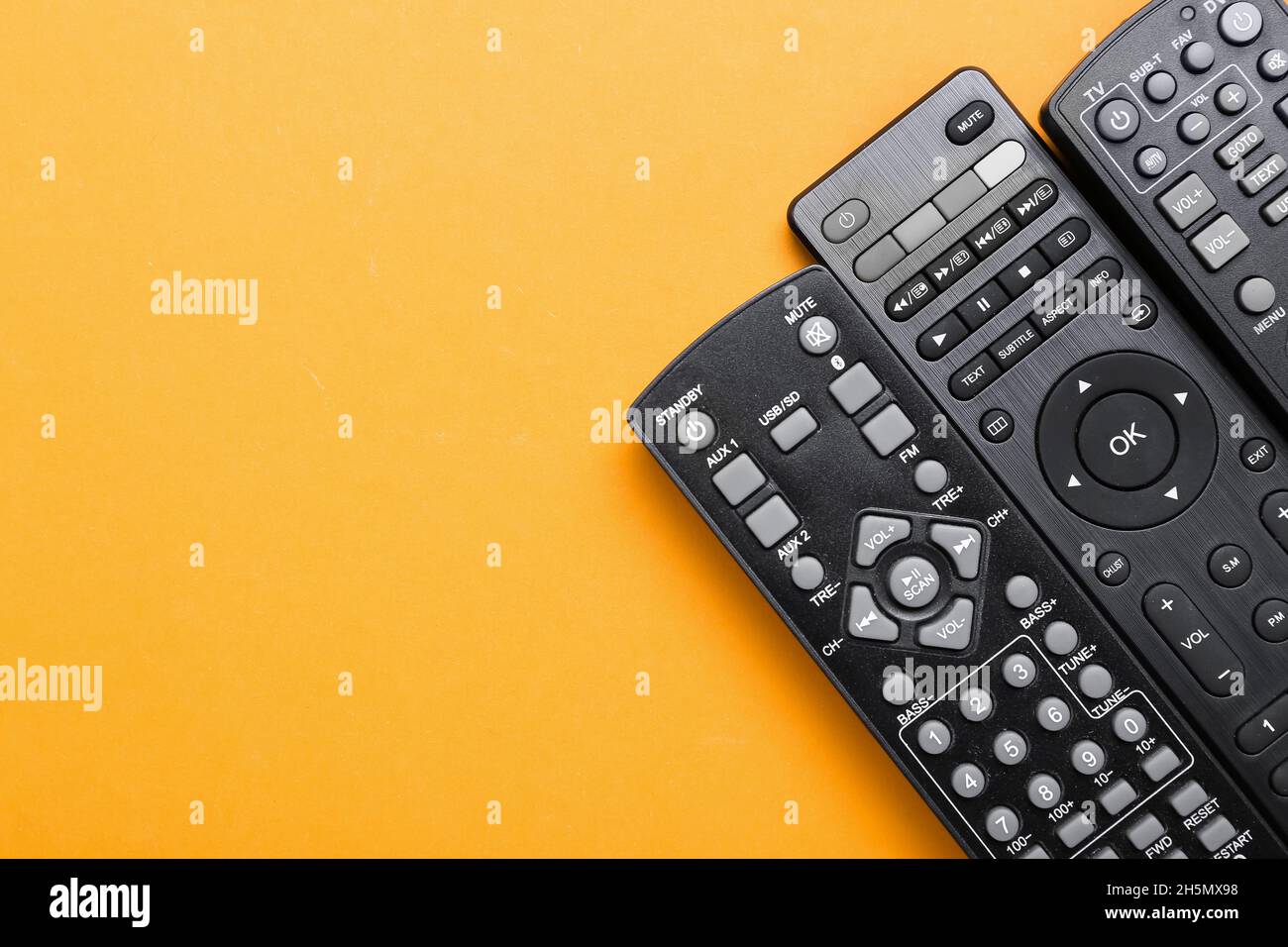 Different TV remote controllers on orange background Stock Photo - Alamy