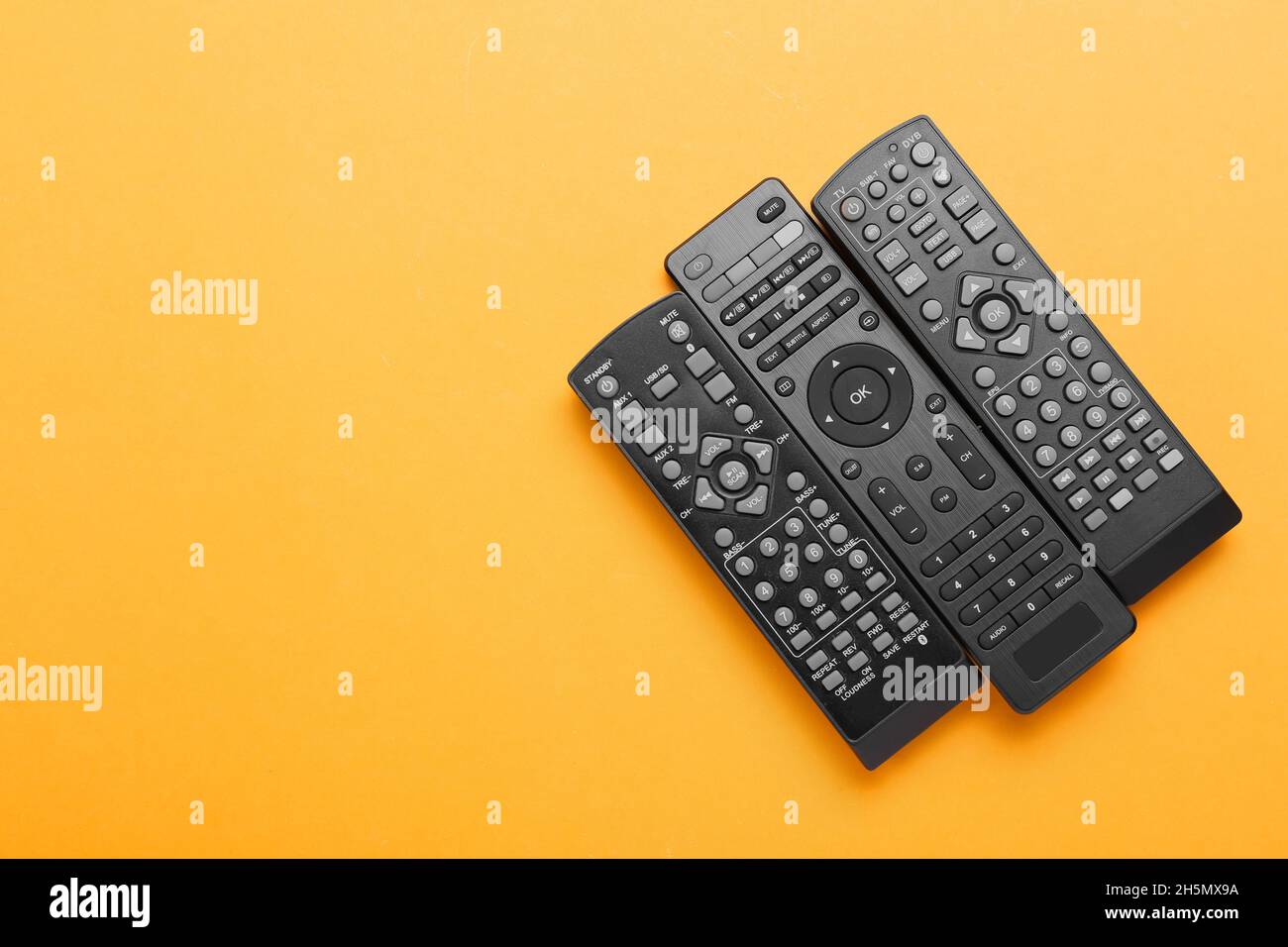 Different TV remote controllers on orange background Stock Photo - Alamy