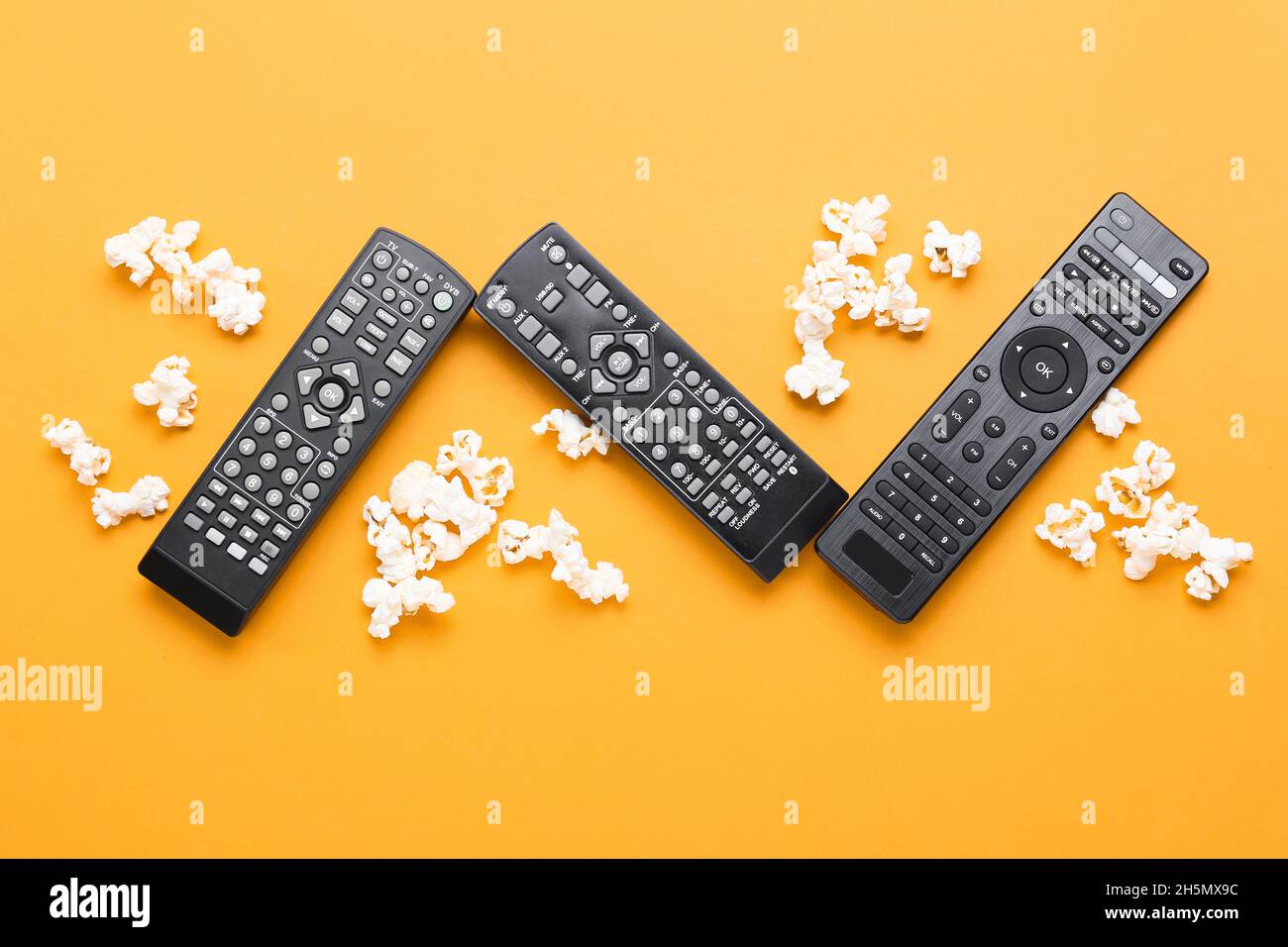 Modern TV remote controllers and popcorn on color background Stock ...