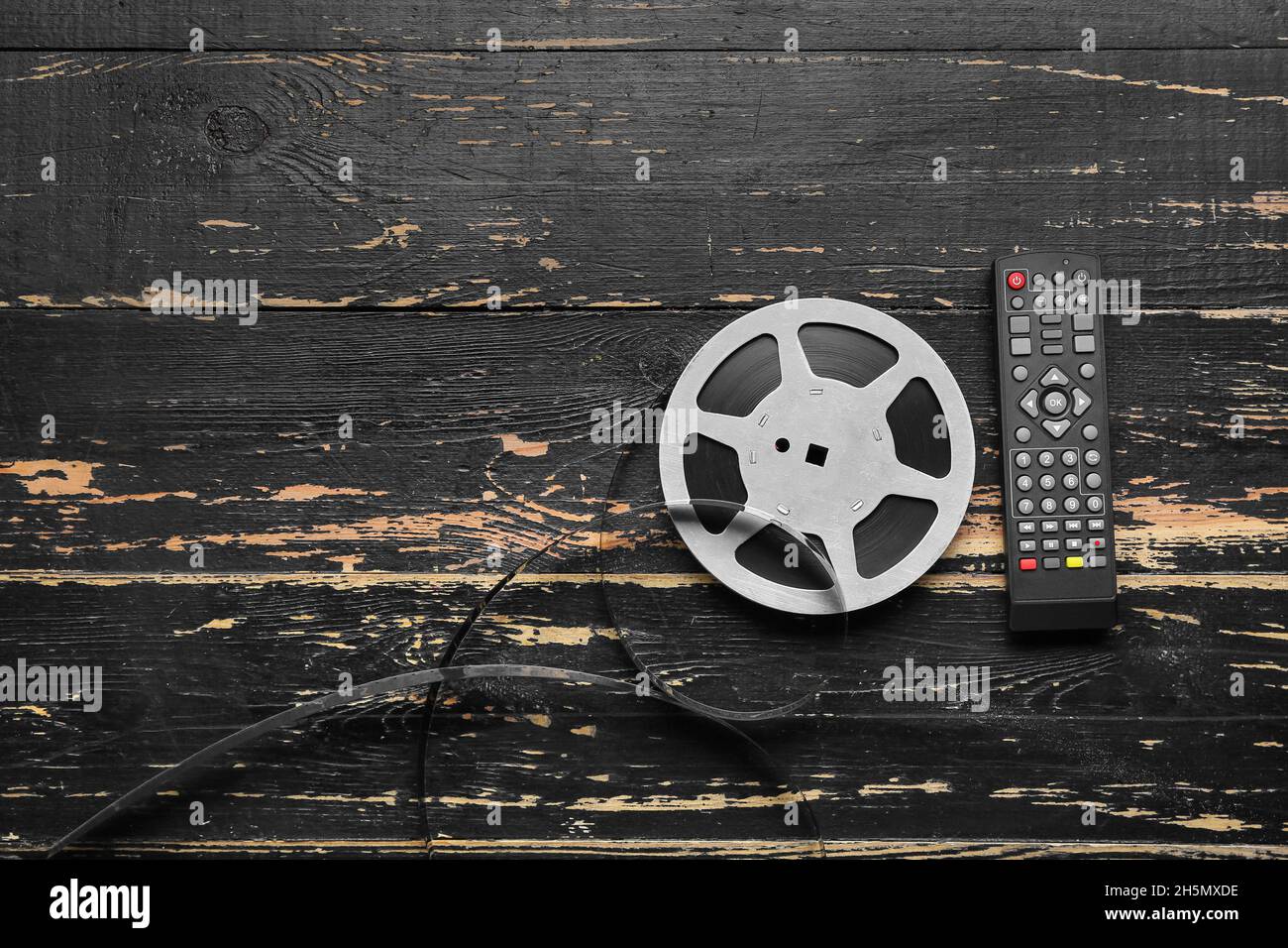 Modern TV remote control and film reel on dark wooden background Stock ...