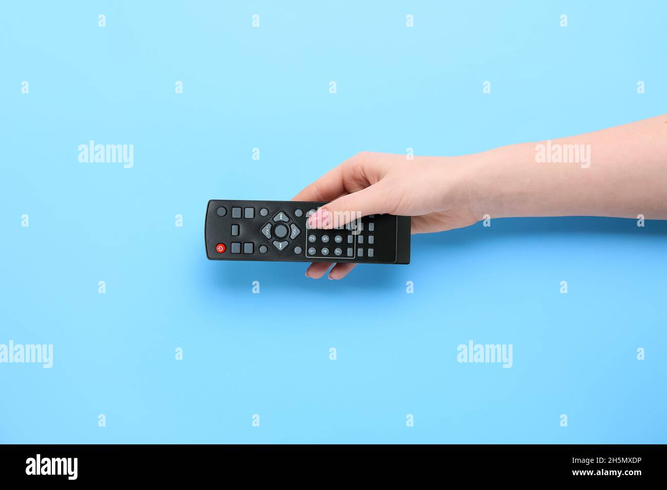 Female hand with TV remote controller on color background Stock Photo ...