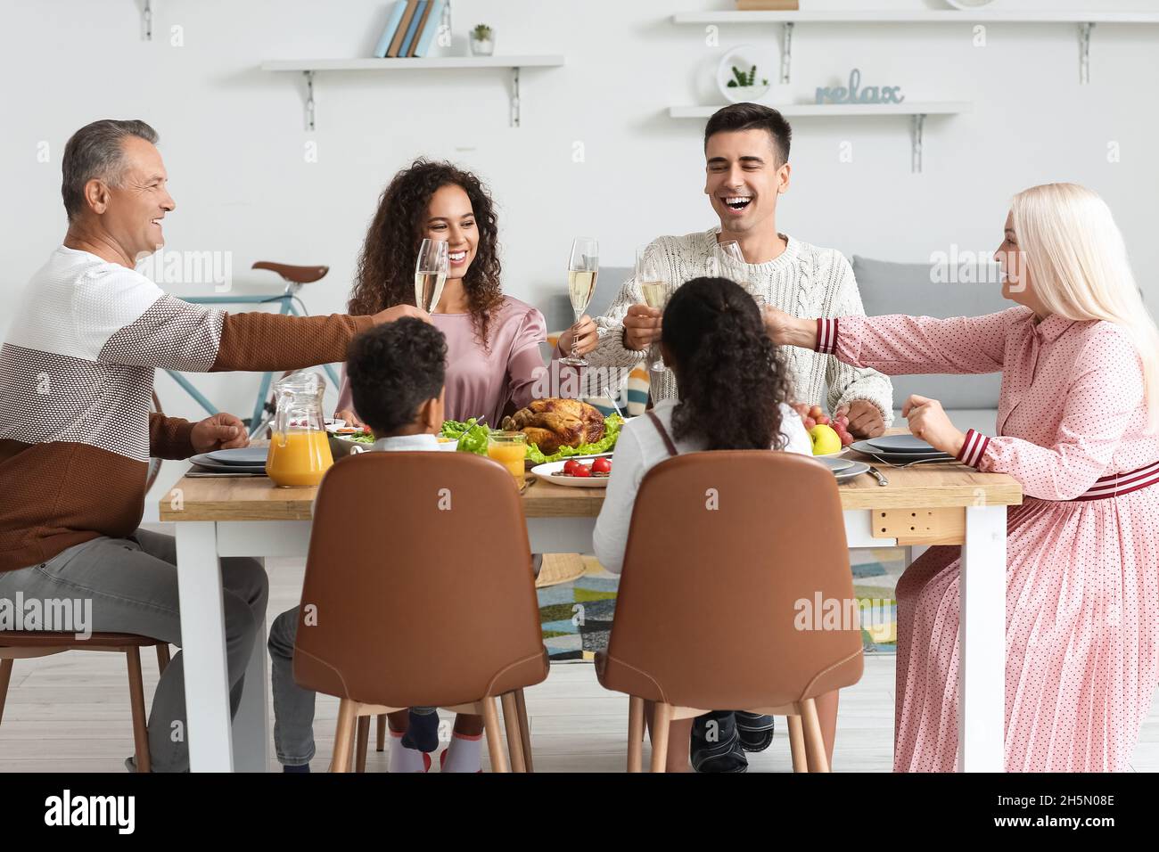 Happy family raising glasses at served table and celebrating ...