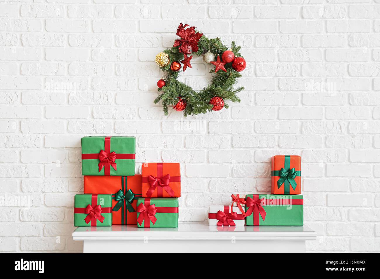 Christmas gift boxes on mantelpiece near white brick wall Stock Photo ...