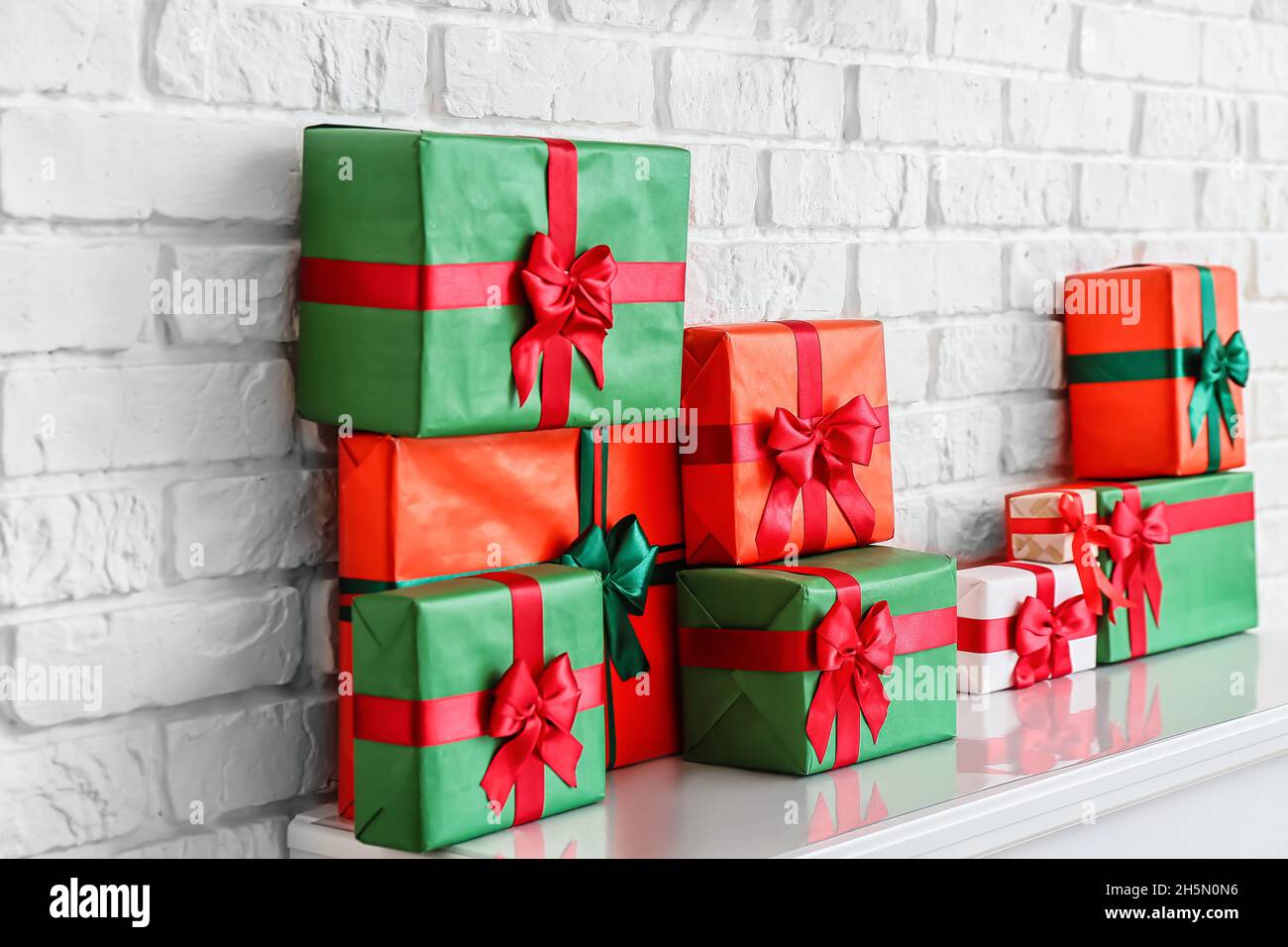 Christmas gift boxes on mantelpiece near white brick wall Stock Photo ...