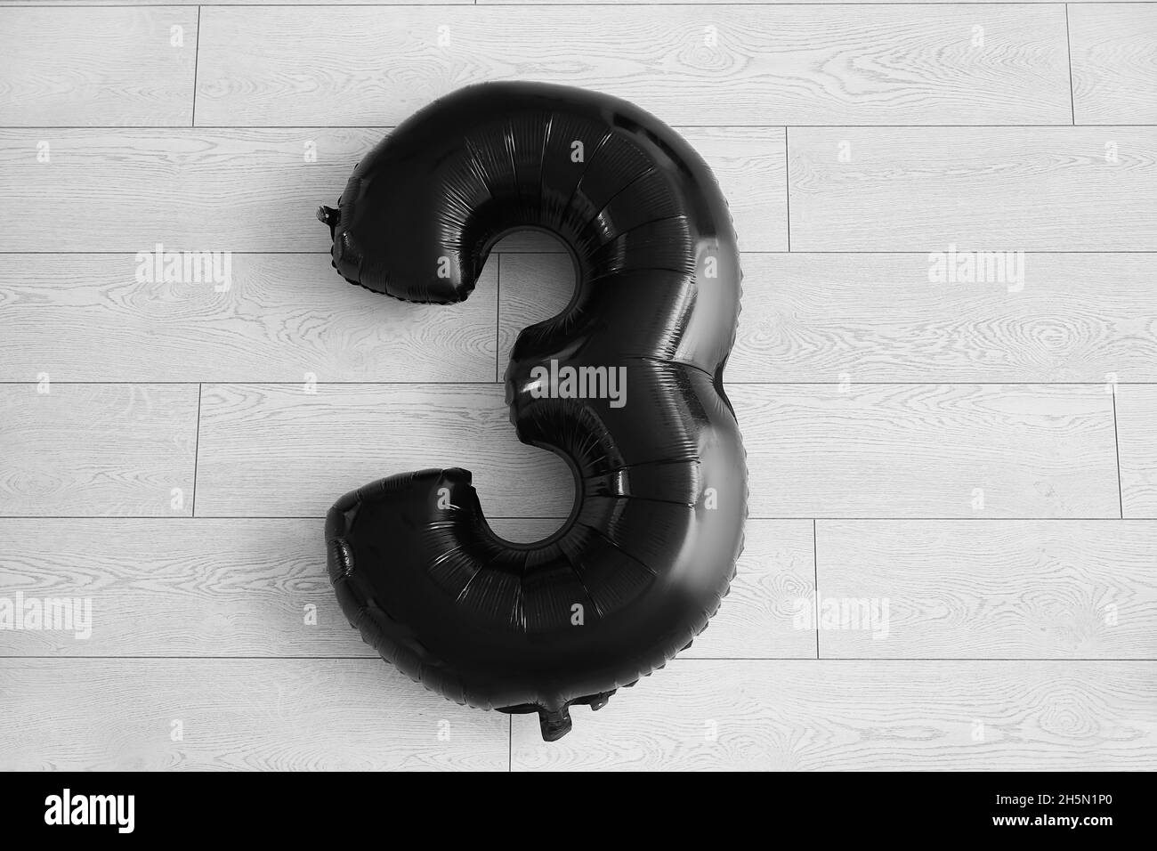 Black balloon in shape of figure 3 on light brick background Stock ...