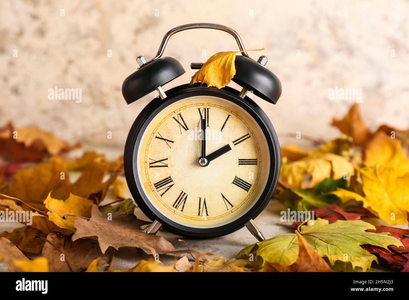 Alarm clock and autumn leaves on grunge background. Daylight saving ...