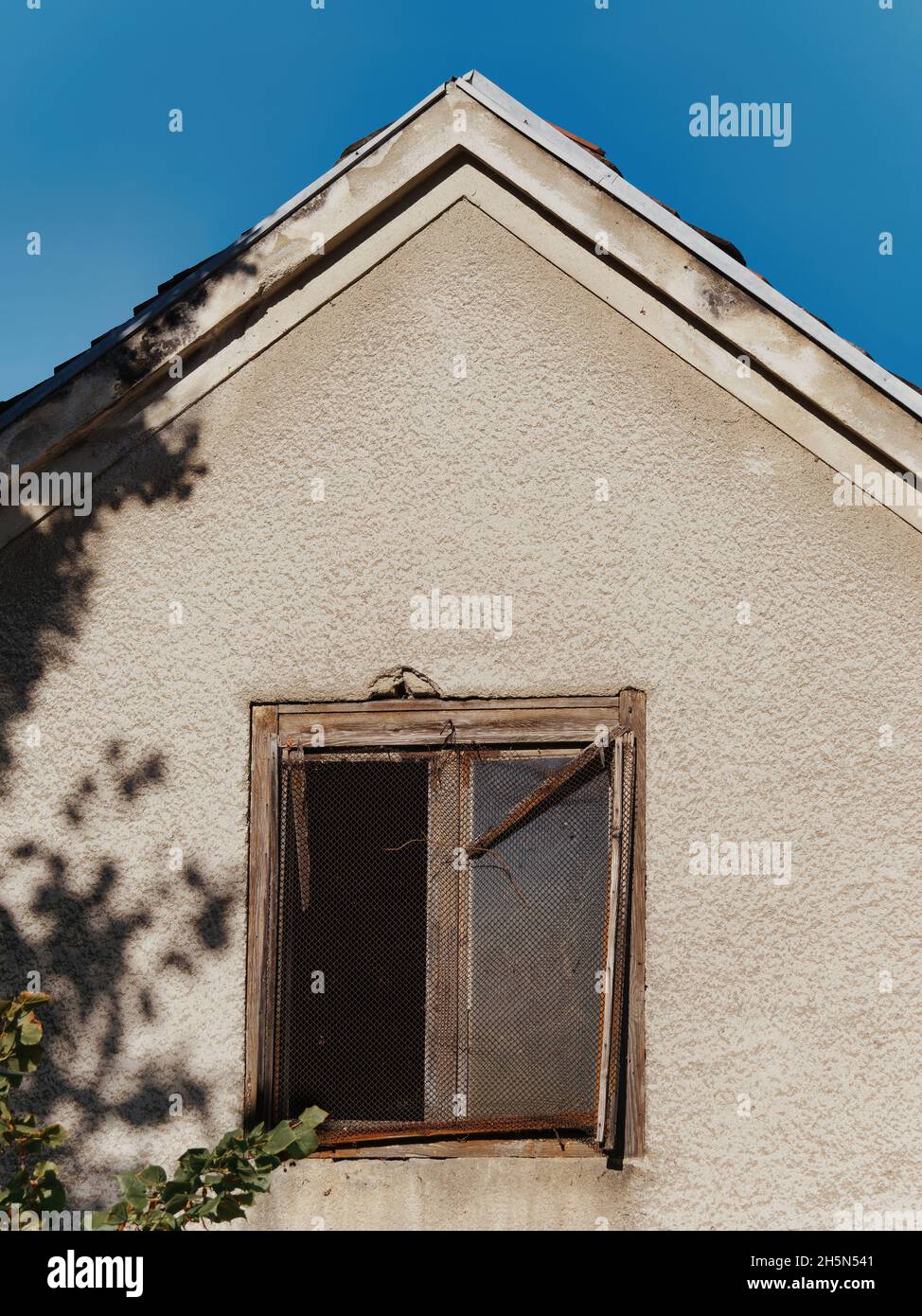 Vertical shot of an old damaged weathered wooden window with a wire ...