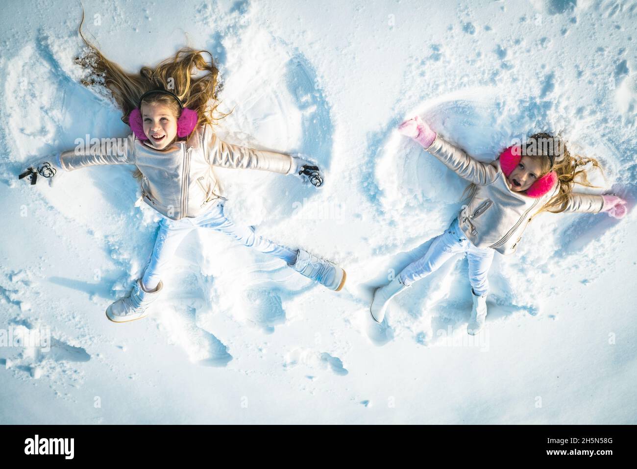 Two children girls on a snow angel wings shows. Funny kids playing and ...