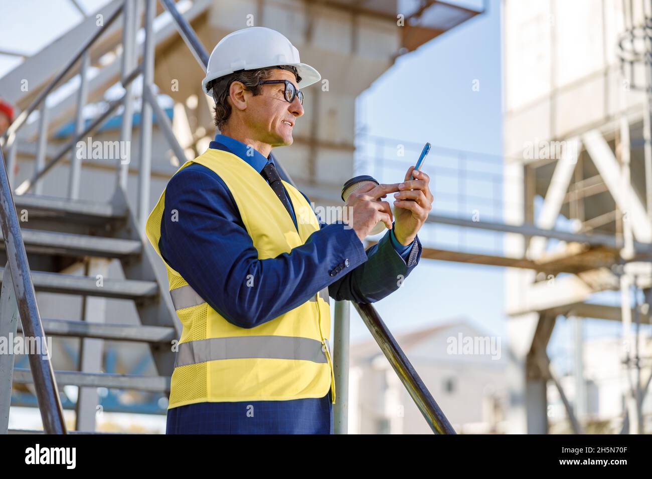 Male engineer using mobile phone outdoors at factory Stock Photo - Alamy