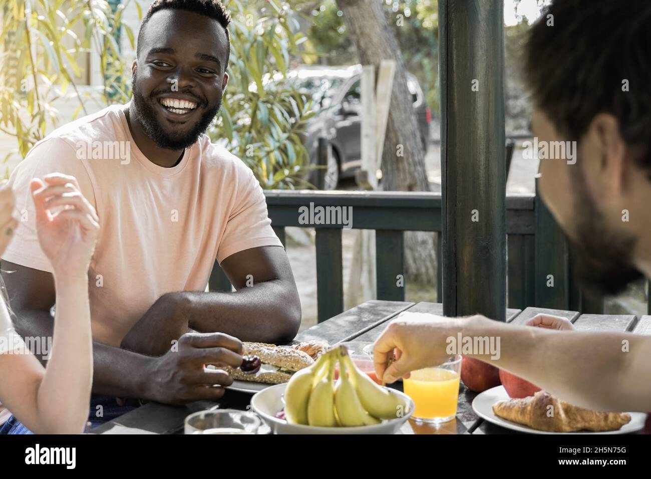 Happy multiracial friends having fun eating outdoor at camping house ...
