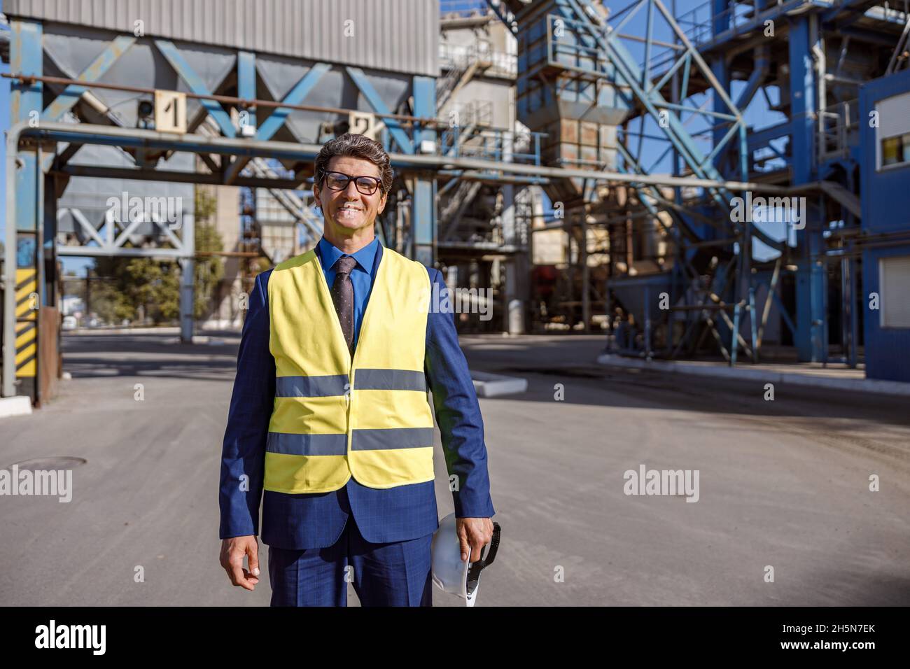 Cheerful male engineer standing outdoors at factory Stock Photo - Alamy