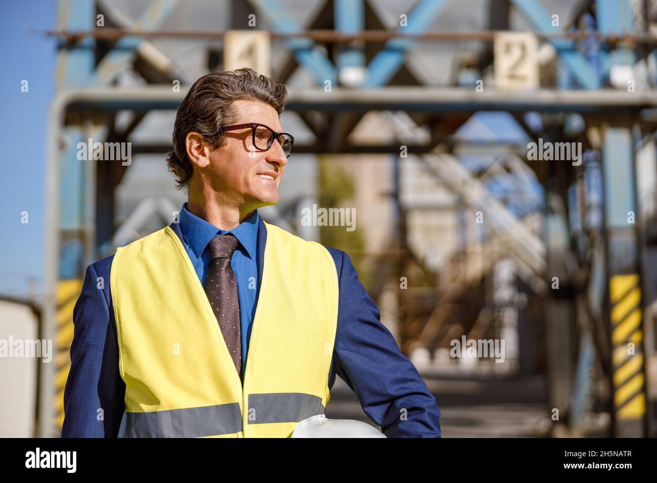 Joyful male engineer standing outdoors at factory Stock Photo - Alamy