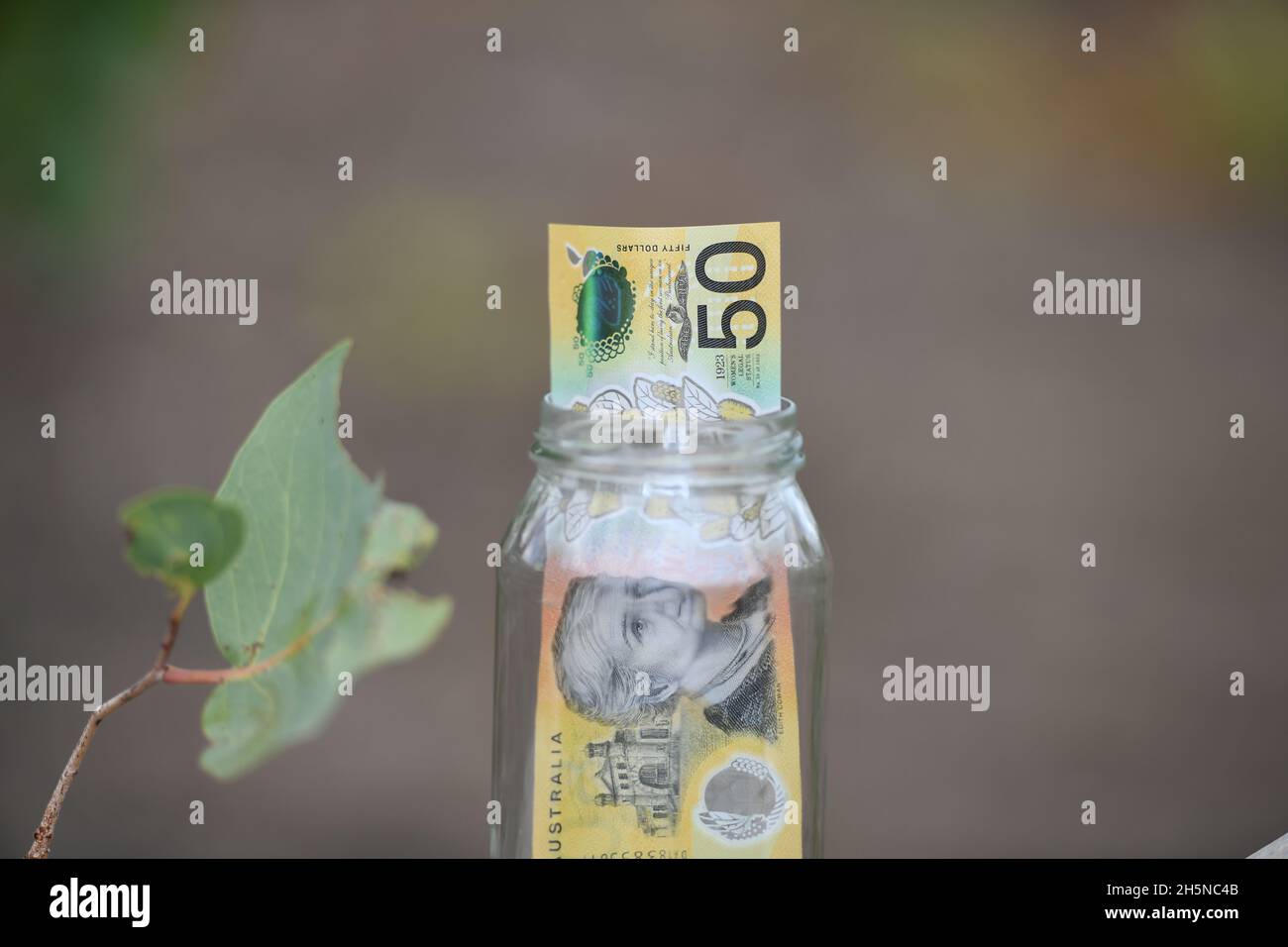 Australian fifty dollar currency note, sitting inside glass jar amidst ...