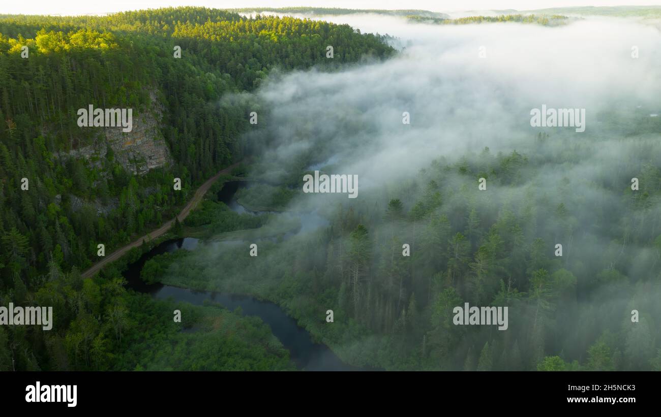 Misty landscape with cliff and forest road Stock Photo - Alamy
