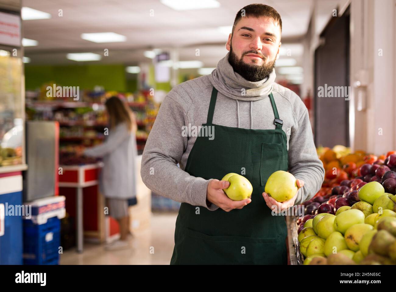 Adult male seller offering ripe apples in grocery shop Stock Photo - Alamy