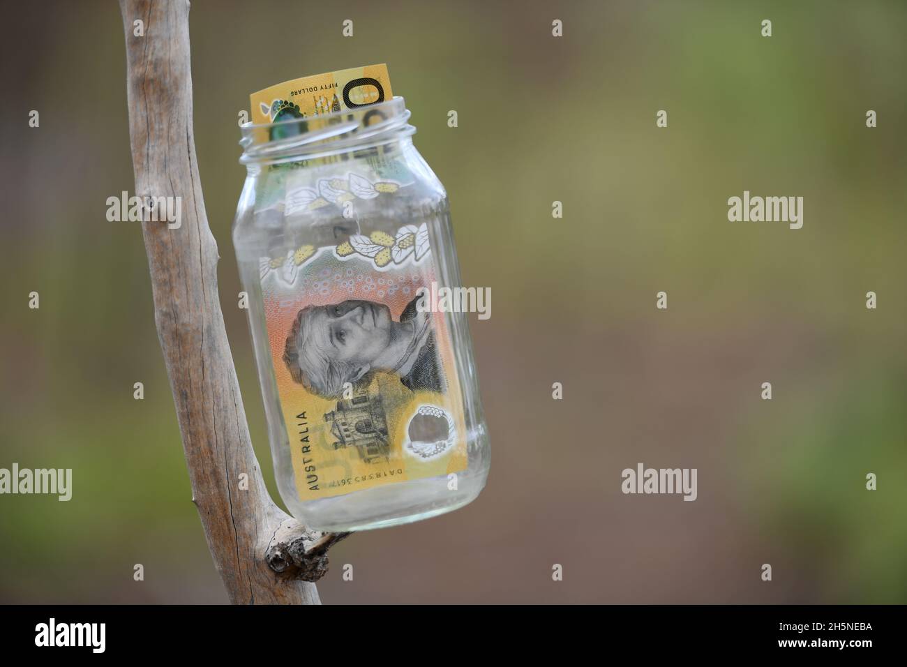 Australian fifty dollar currency note, sitting inside glass jar amidst ...