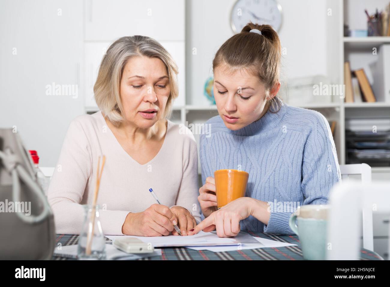 Woman and adult daughter fill out paperwork Stock Photo - Alamy