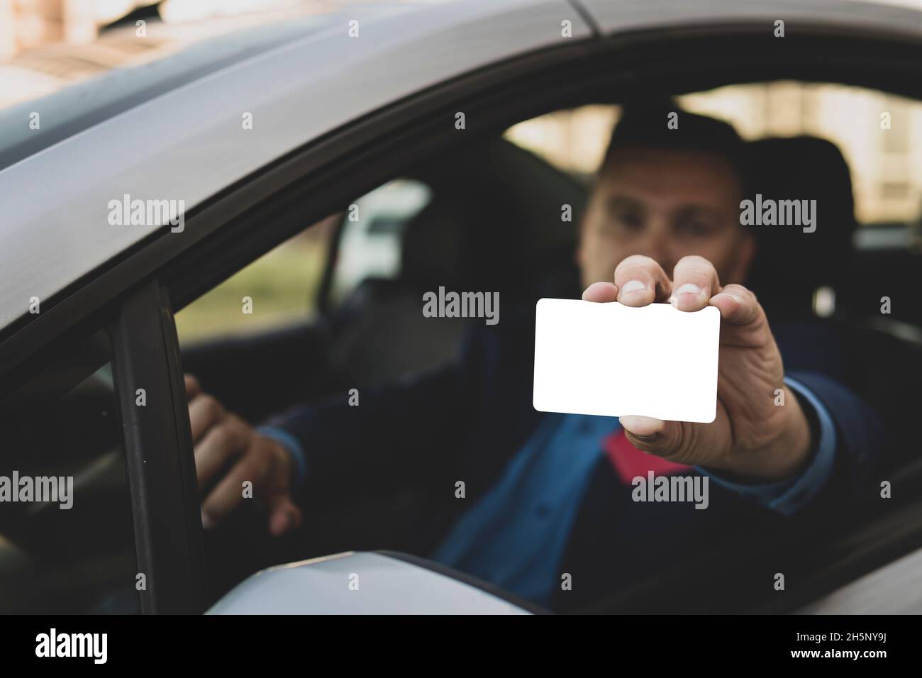 Young man with sitting in car showing an empty white card. Driver has ...