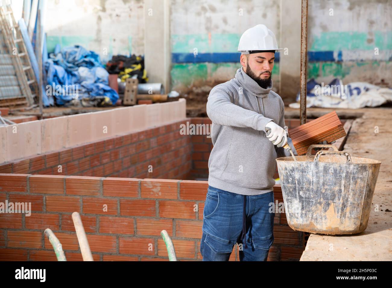 Builder working with red brick Stock Photo - Alamy