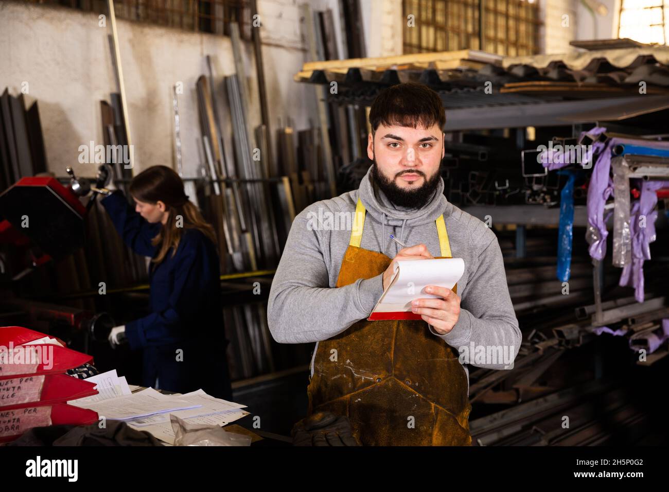 Craftsman of metalworking shop writing in notebook Stock Photo - Alamy