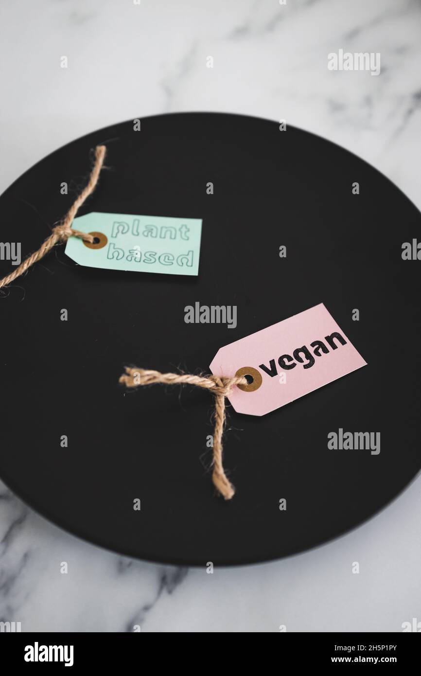plant-based and vegan labels on top of black dining plate on marble ...