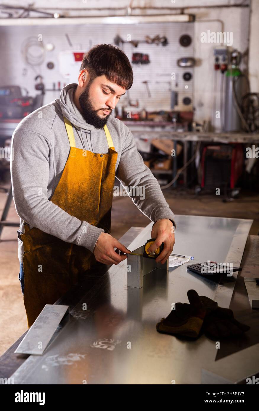 Workman measuring metal parts Stock Photo - Alamy