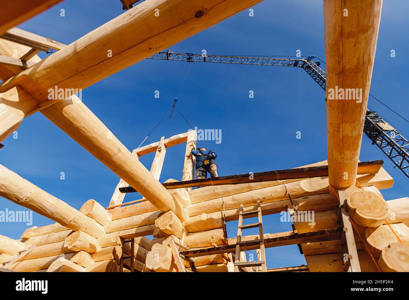 Worker carpenter builder working on roof house of log structure ...
