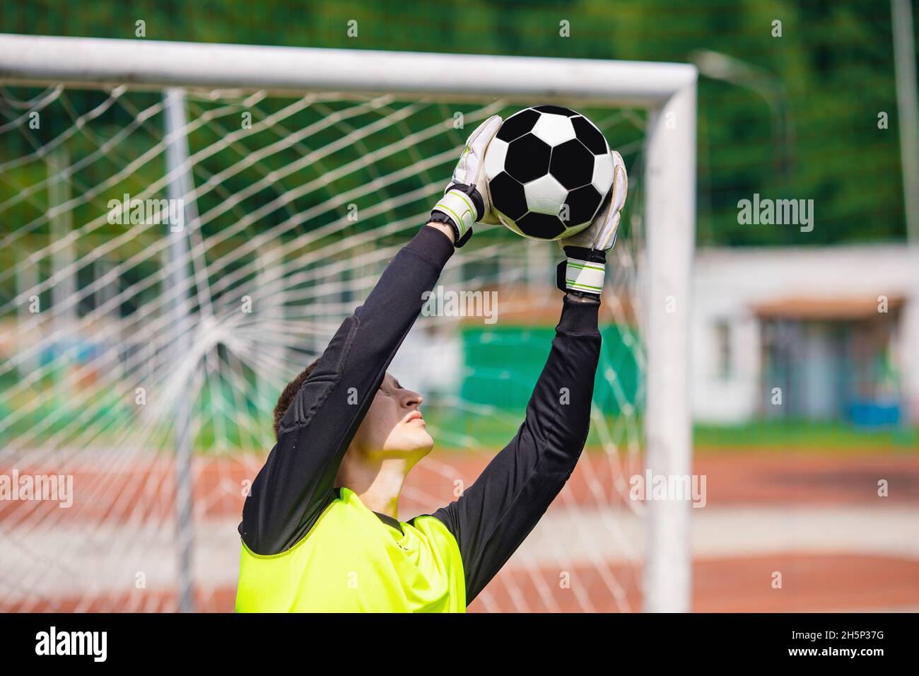 Goalkeeper soccer man catching ball in stadium, action moment of sport ...