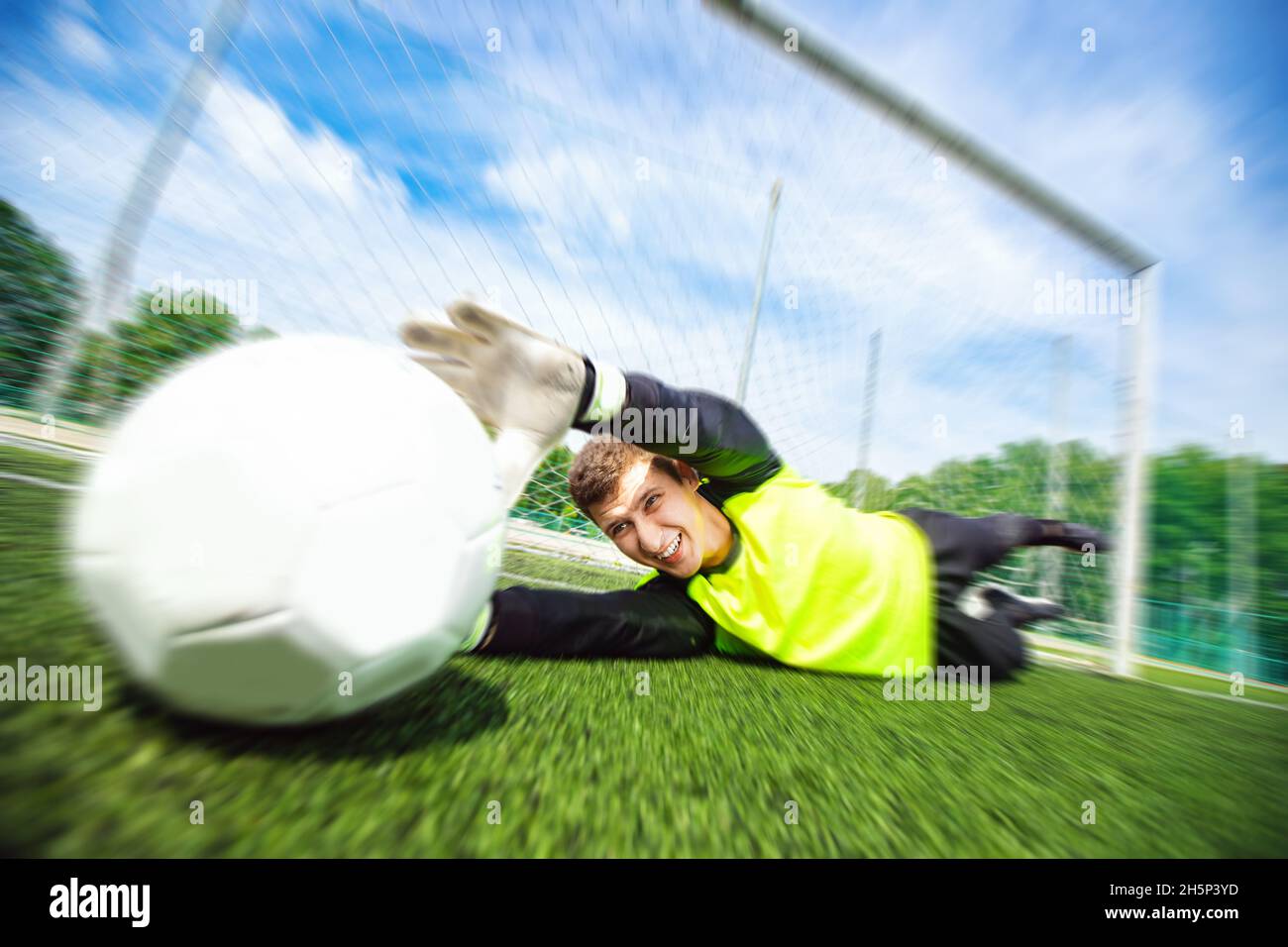 Goalkeeper soccer man catching ball in stadium, action moment of sport ...