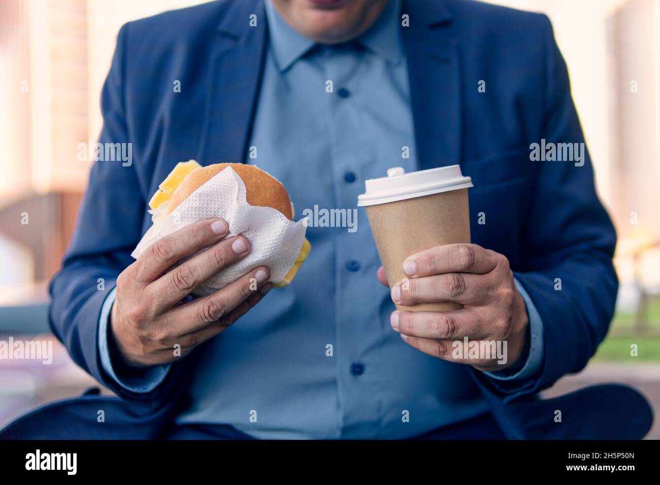 The concept of junk food on the lunch break. Businessman eats unhealthy ...