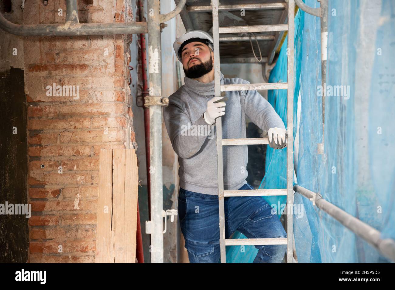 Civil engineer climbing up ladder at building site Stock Photo - Alamy