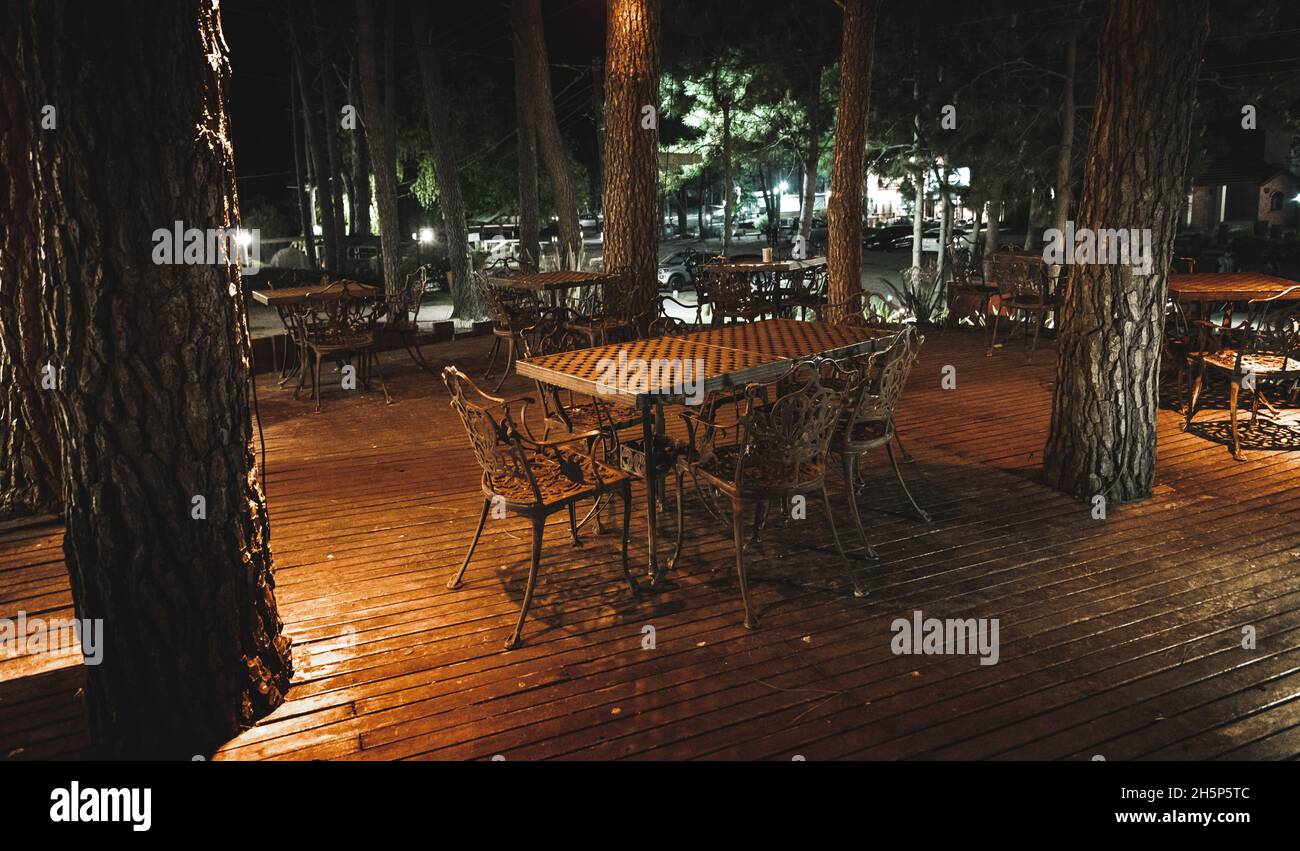 Night scene of wooden deck of an elegant outdoor bar, illuminated by ...