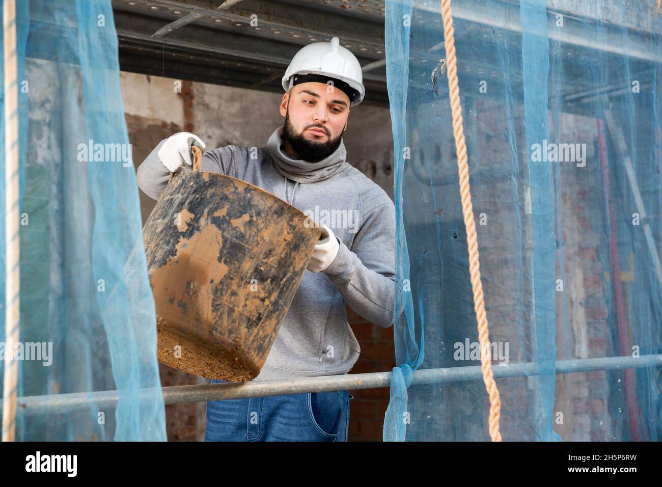 Contractor carrying bucket with cement mortar Stock Photo - Alamy