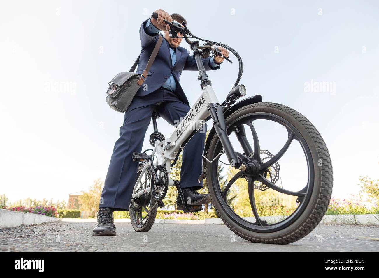 businessman commuter with electric bicycle traveling to work in city. A ...
