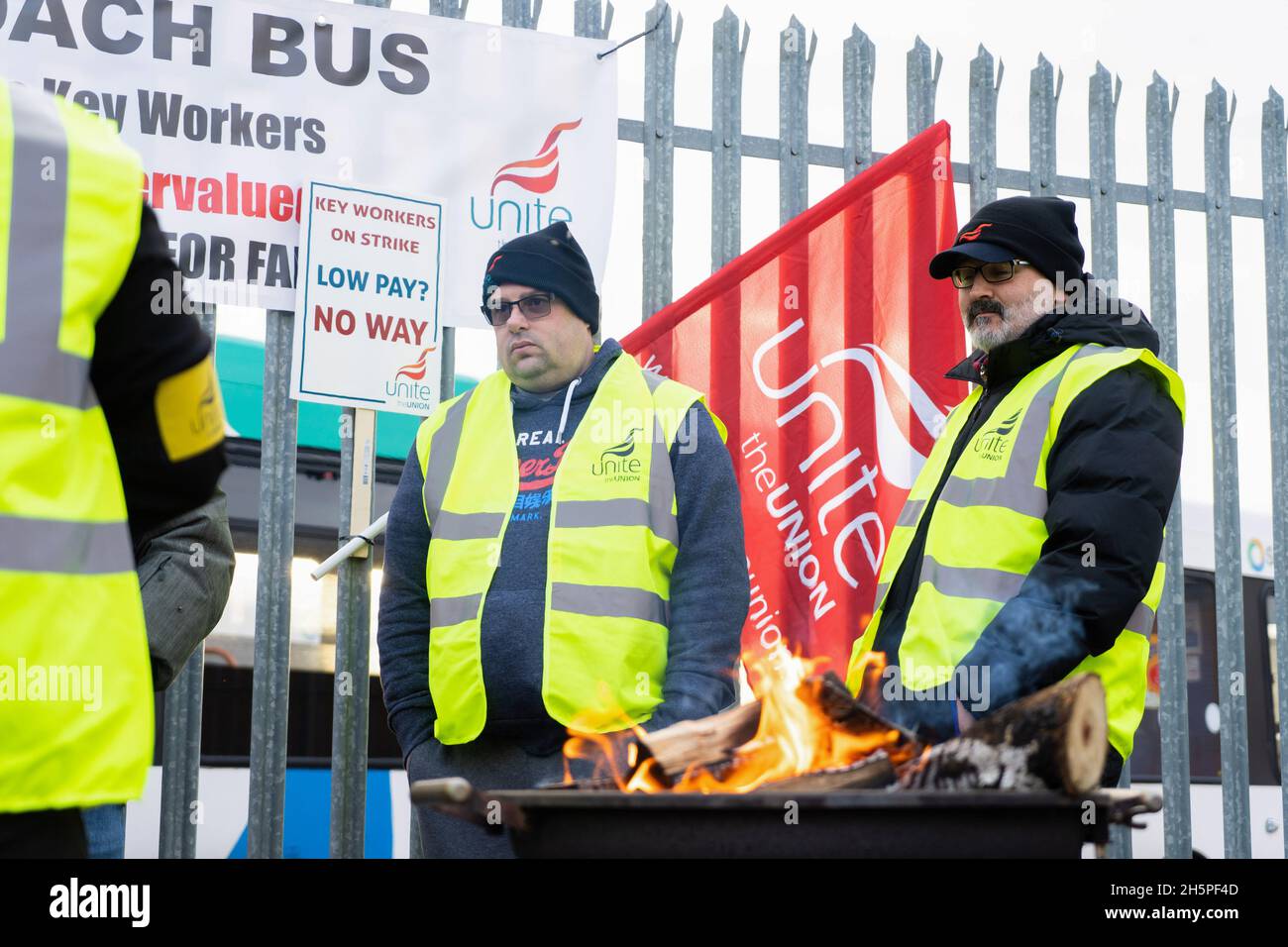 Striking bus drivers stand in front of a fire on a picket line outside ...