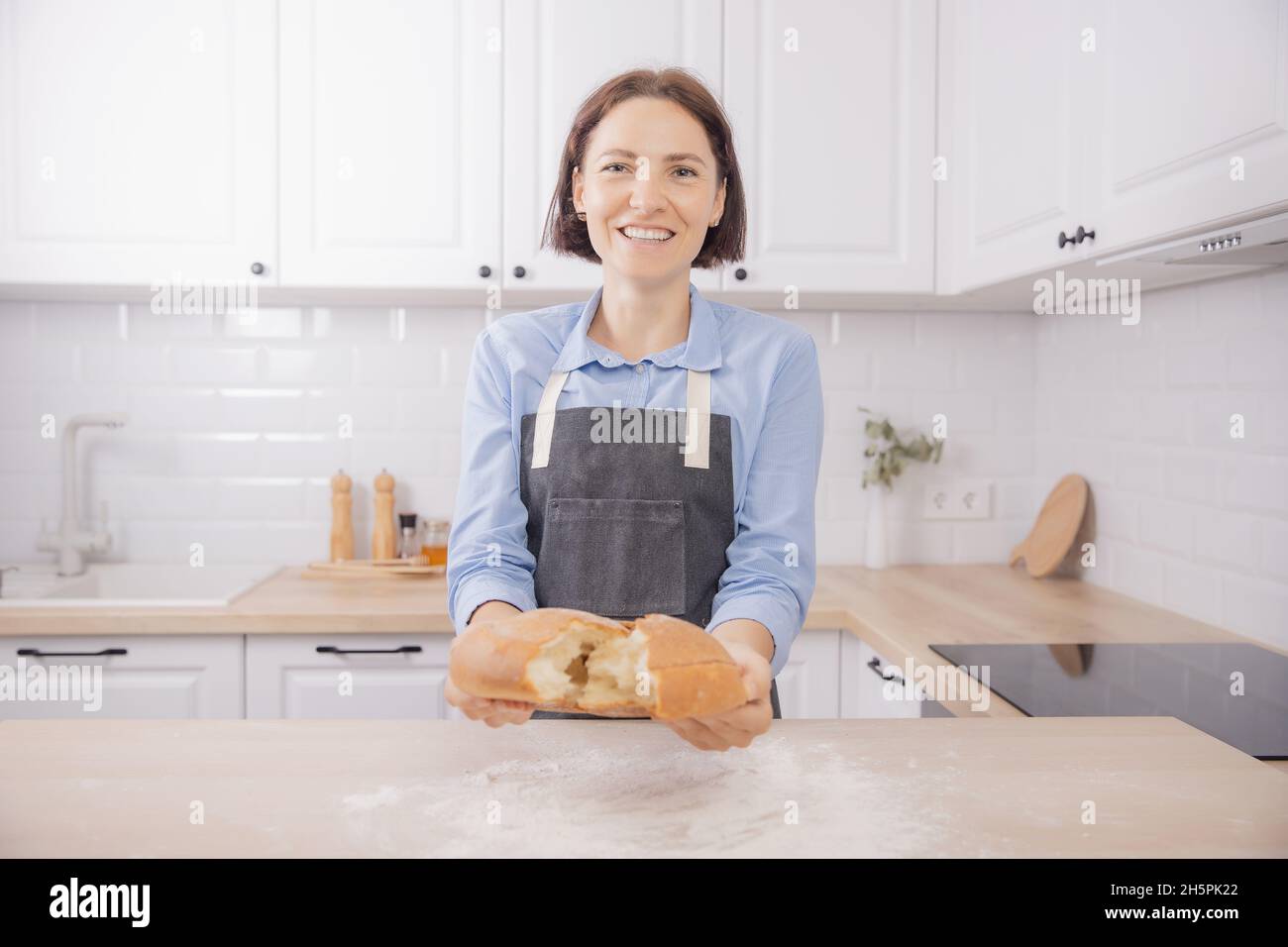 Baker hands break hot fresh round wheat bread into two halves, crunch ...