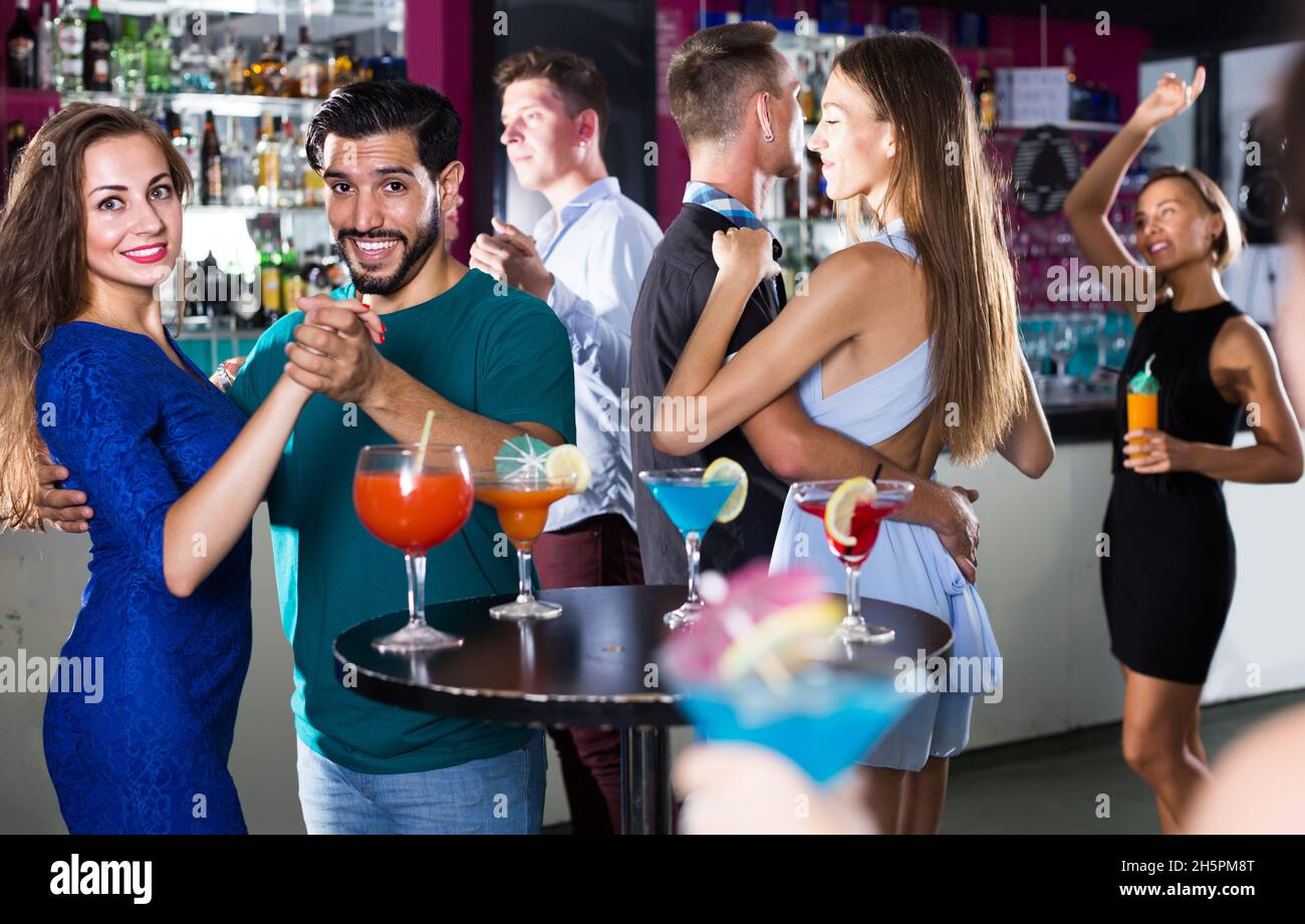 Young smiling women with men are dancing in pairs in the nightclub ...