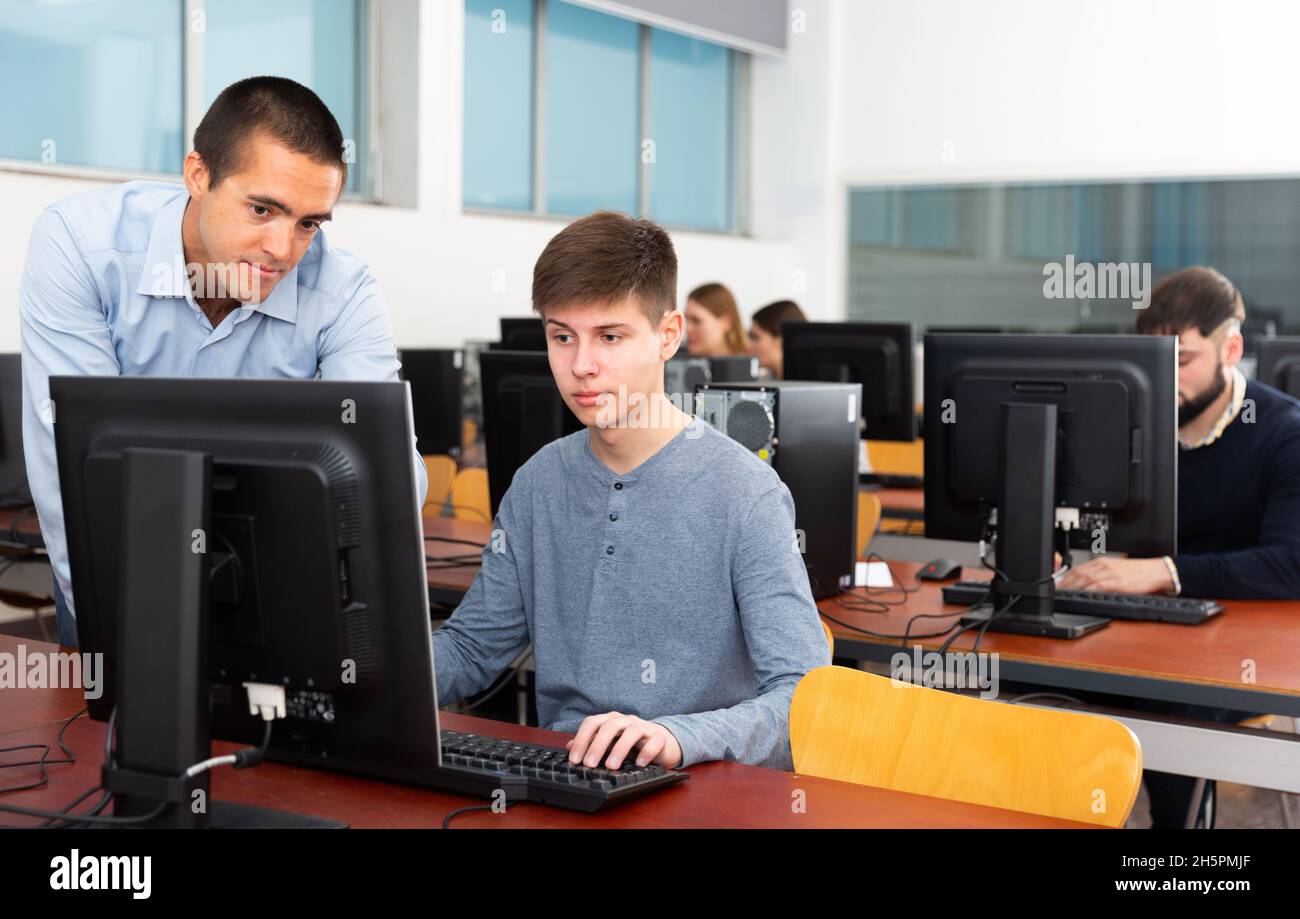 Male trainer helping young female student in computer class Stock Photo ...